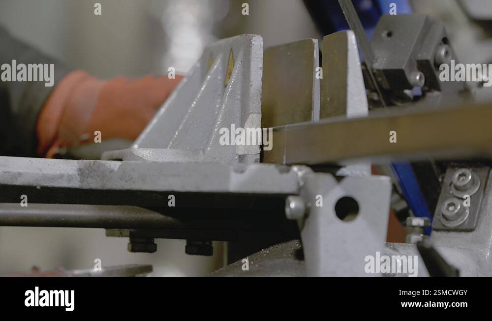 Cutting steel bars, Hands placing the bar in the clamps of an electric ...