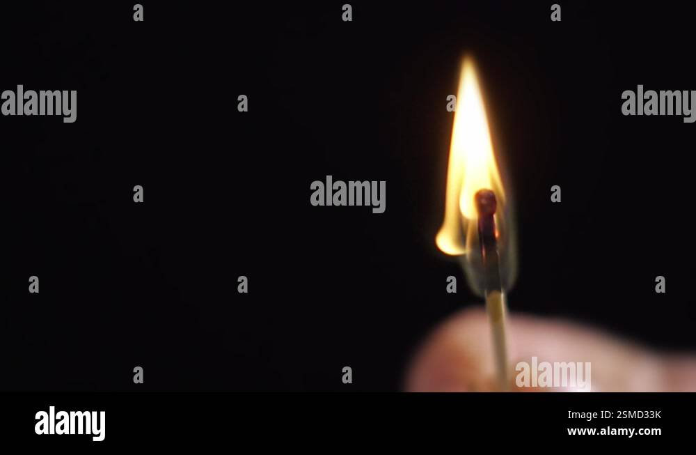 Hand holding burning lucifer with huge flame in black screen background ...