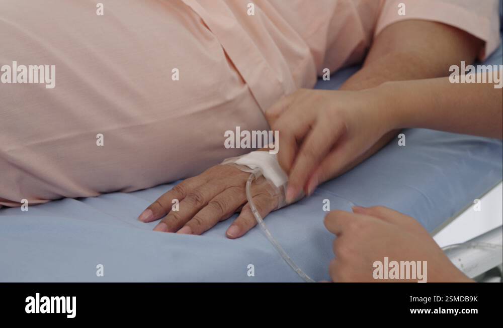 Female nurse takes care of inserting an IV line for an elderly Asian ...