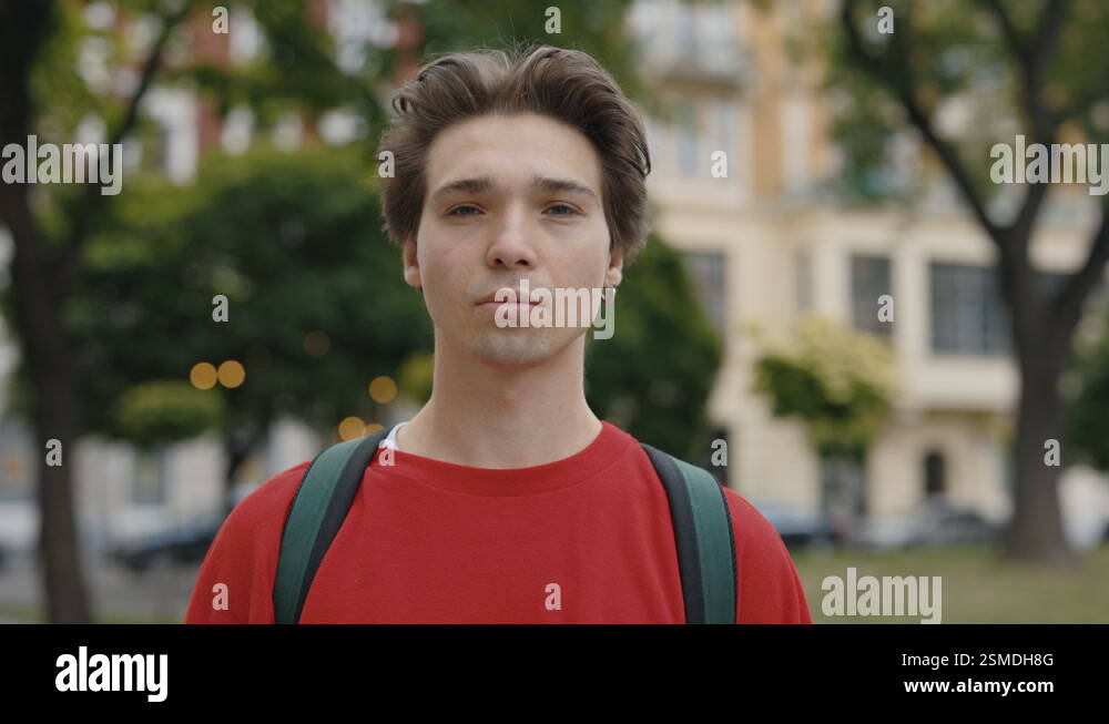 Portrait of young Caucasian male tourist with backpack in city street ...
