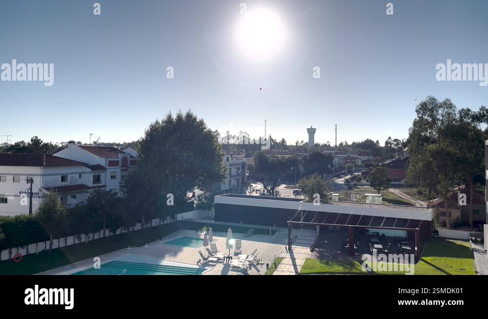 Daytime capture with sun on horizon over peaceful residential area with ...