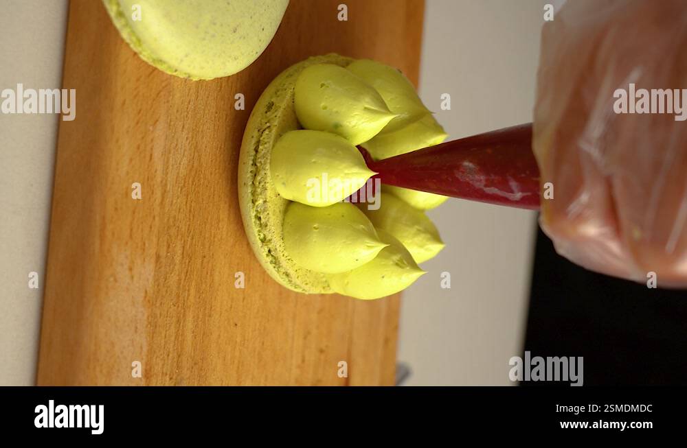 The French pastry chef adds strawberry sauce filling to the macarons ...