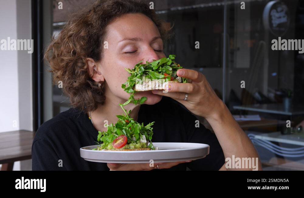 Hungry woman tastes healthy food dish with appetite. Face conveys ...