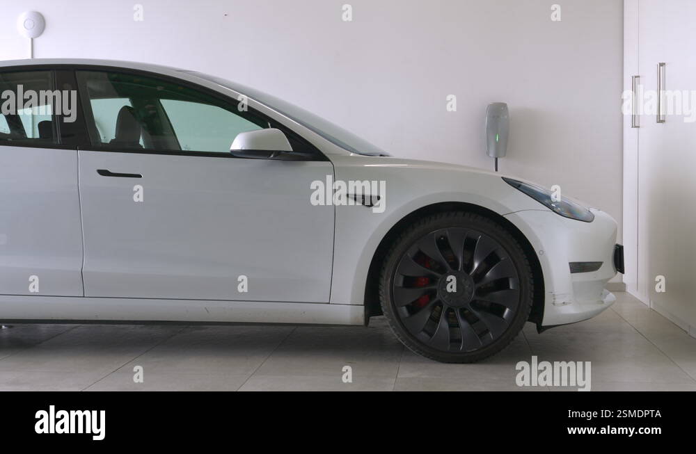 CLOSE UP: Scratched Tesla car connected to a charging station in home ...