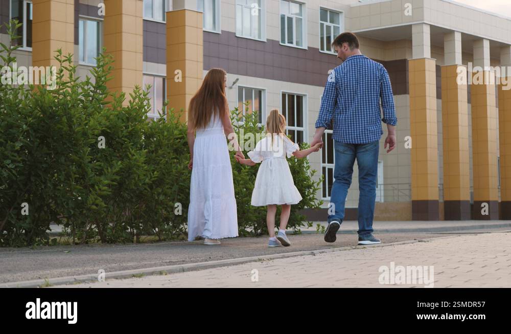 Mother and father take little daughter to school holding hands in city ...