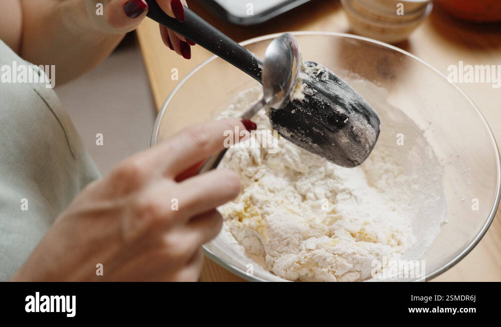 Woman cleans the black spatula from the dough that stuck to it during ...