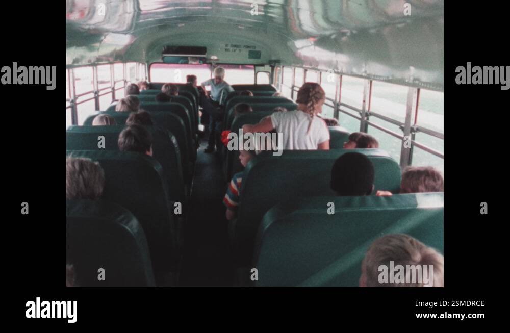 1980s: Children use a handrail to enter a school bus. They sit in seats ...