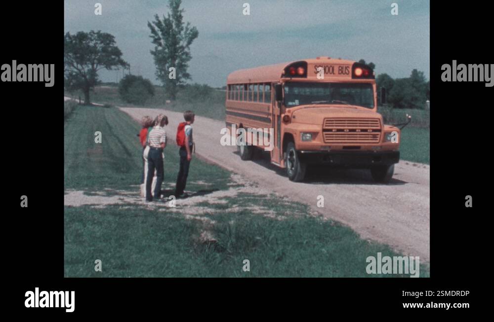 1980s: Children line up in a field next to a dirt road. Bus stops on ...