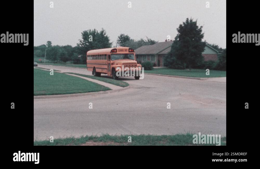 1980s: Children ride in a school bus. Boy hands a book to another boy ...