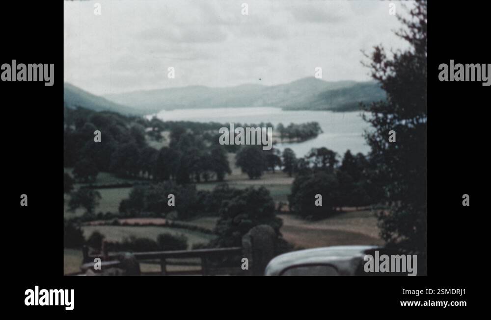1960s: Lake in the hills of the countryside. People walking past the ...