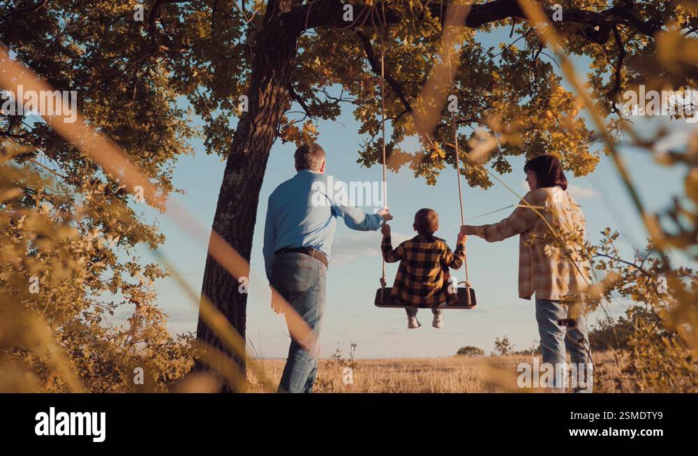 Father and mother simultaneously push son on homemade swing grabbing ...