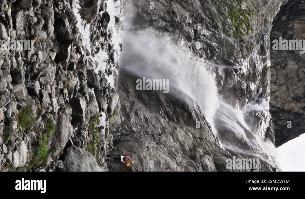 powerful waterfall several cascades down from cliff At its foot is a ...