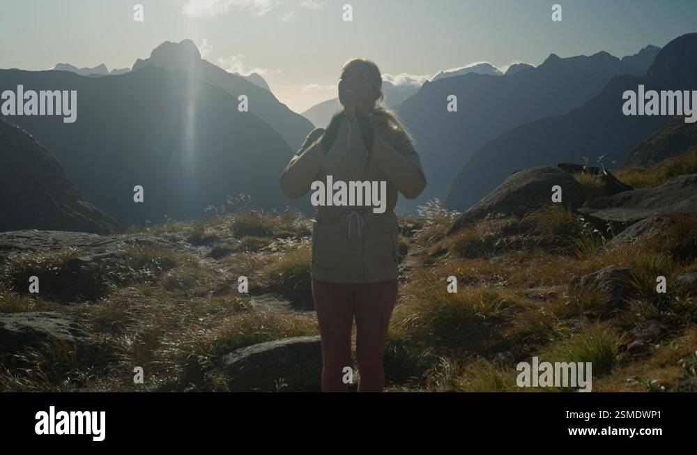 Woman reaching mountain peak showing joyful emotions caused by stunning ...