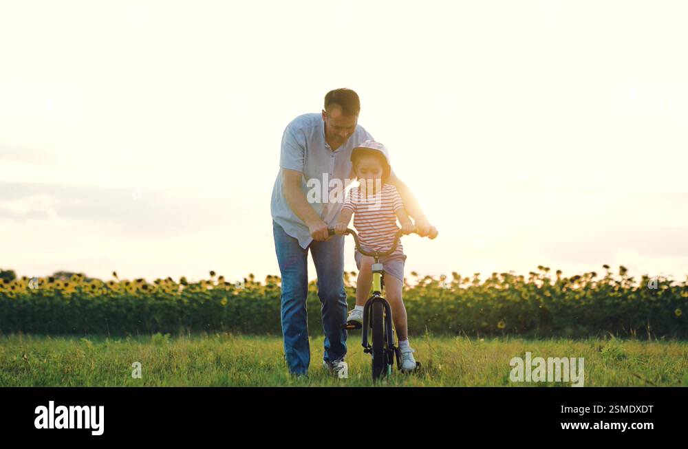 Father holds bicycle while little daughter learns ride vehicle in rural ...
