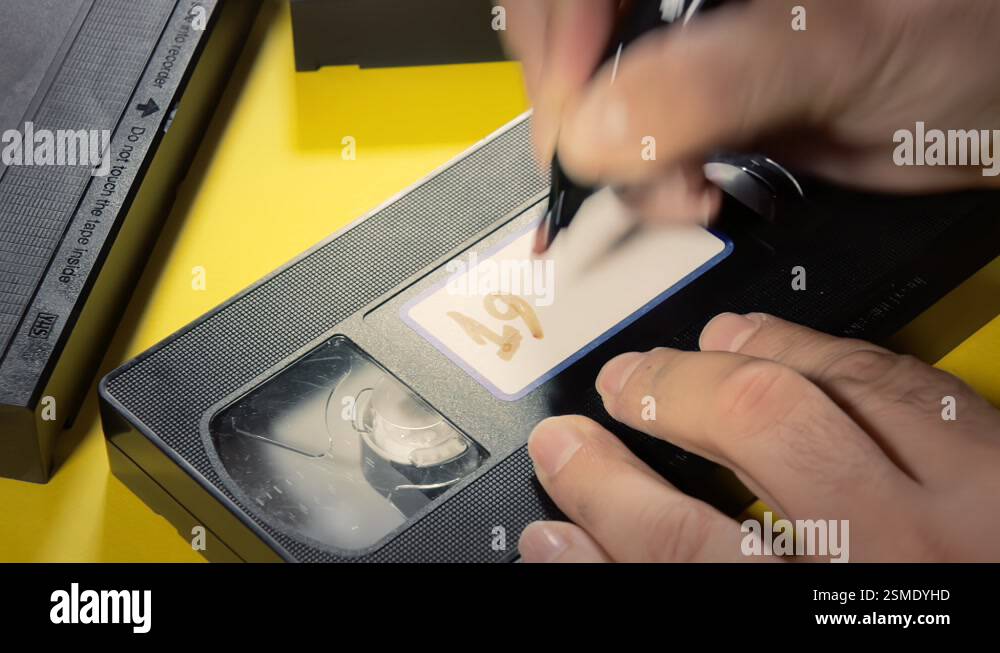 Writing the text 1990's on the white label of an old VHS videotape ...