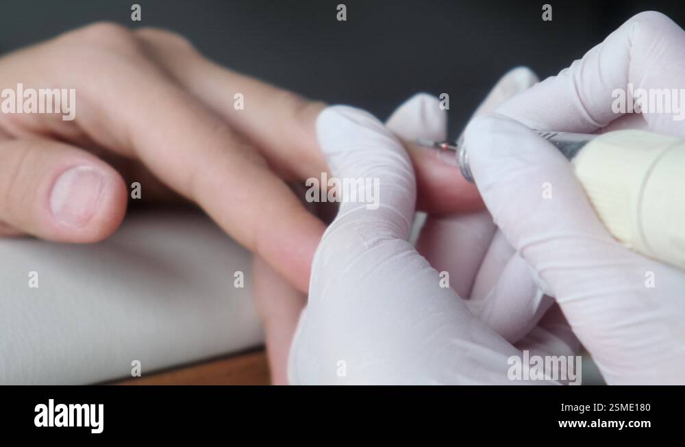 Manicure care procedure. Cleaning a hand nail with a milling cutter ...