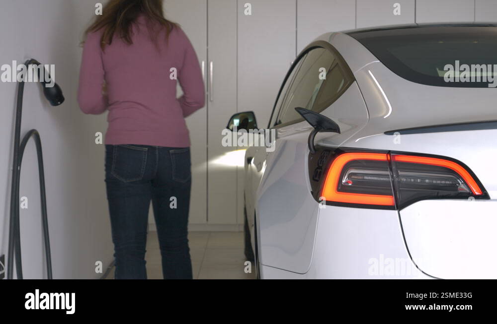 CLOSE UP: Woman disconnects Tesla car from home charging station and ...