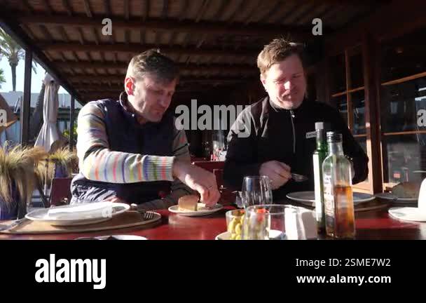 Andalucia, Spain - January 30, 2025 - Two men dining outdoors at a ...