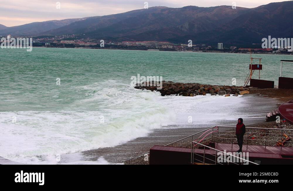 Winter storm on a pebble beach. Large sea waves, all in foam, flood the ...