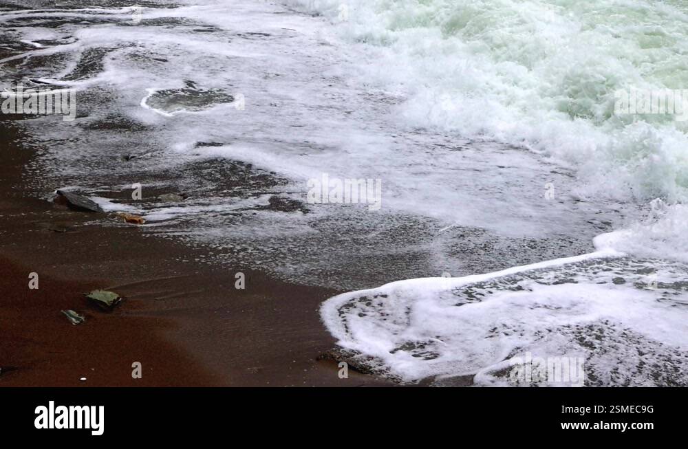 Winter storm on a pebble beach. Large sea waves, all in foam, flood the ...