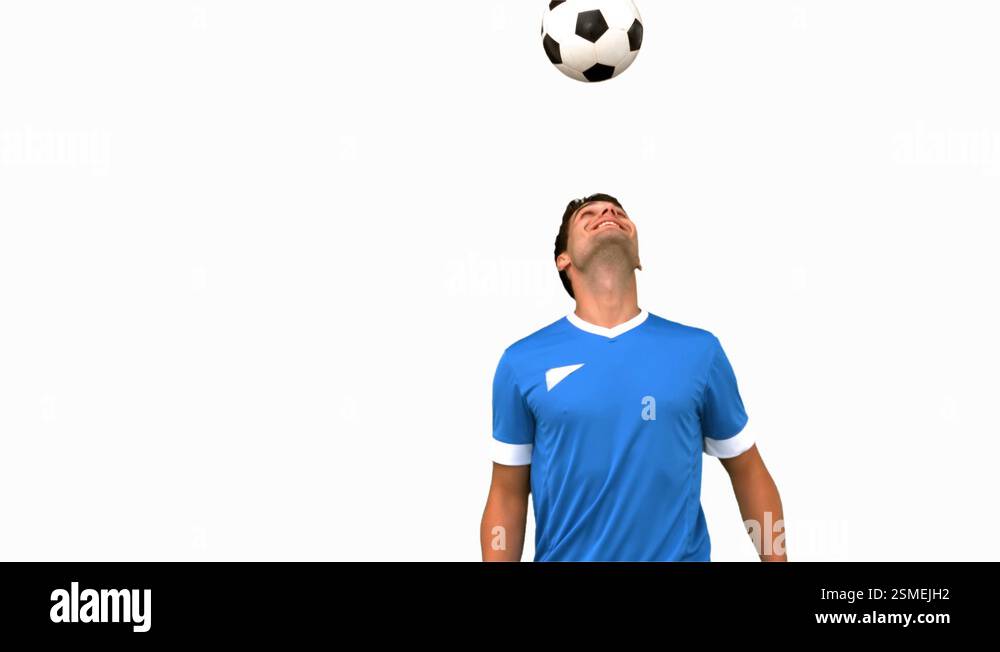 Man juggling a football with his head on white screen in slow motion ...