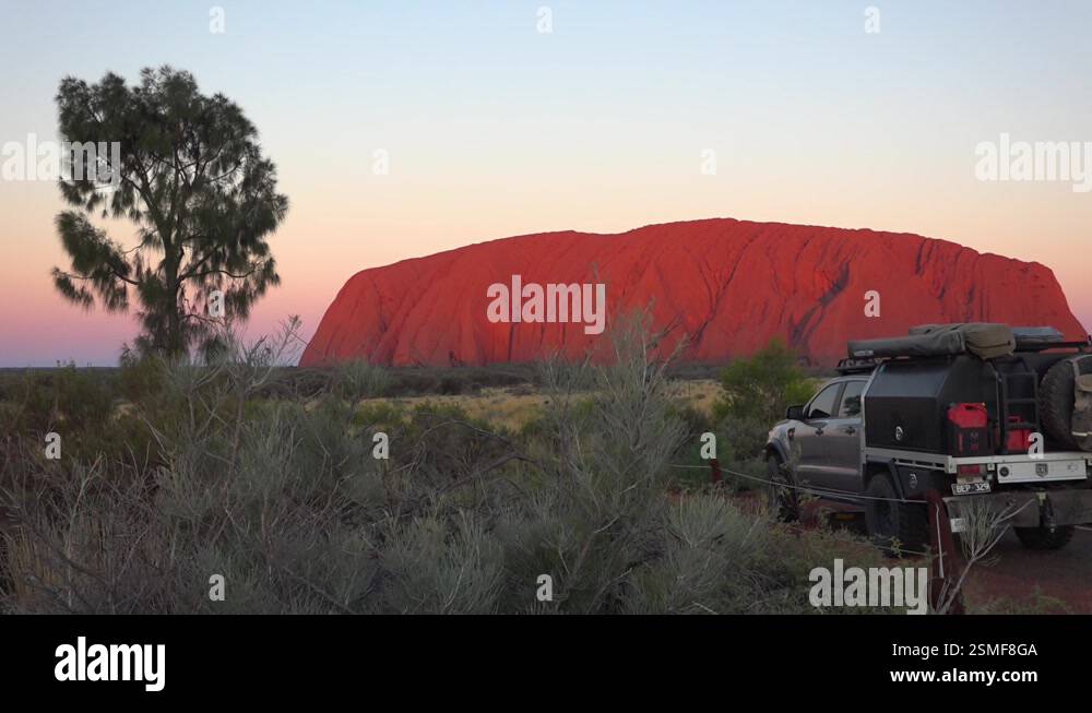 View of Uluru at sunset and parked off-road tourist vehicle in the ...