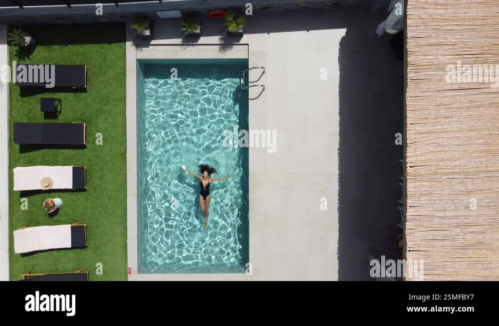 Drone flies over an outdoor pool in bird's eye view - Woman in swimming ...