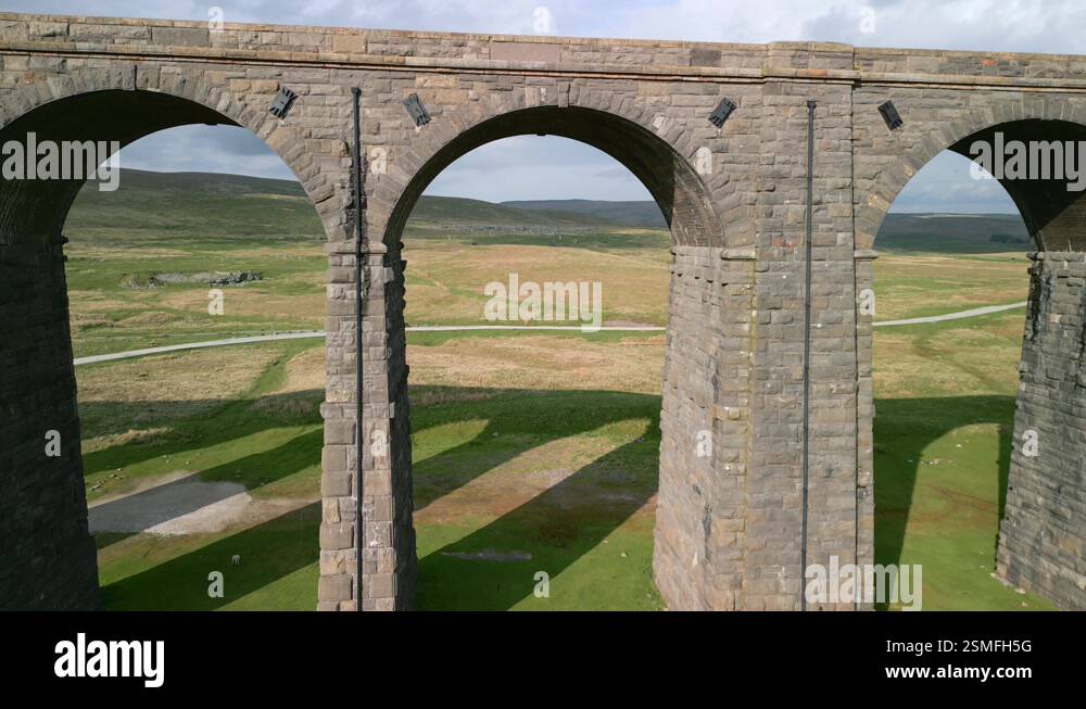 Flying through tall stone arches of viaduct railway bridge spanning ...