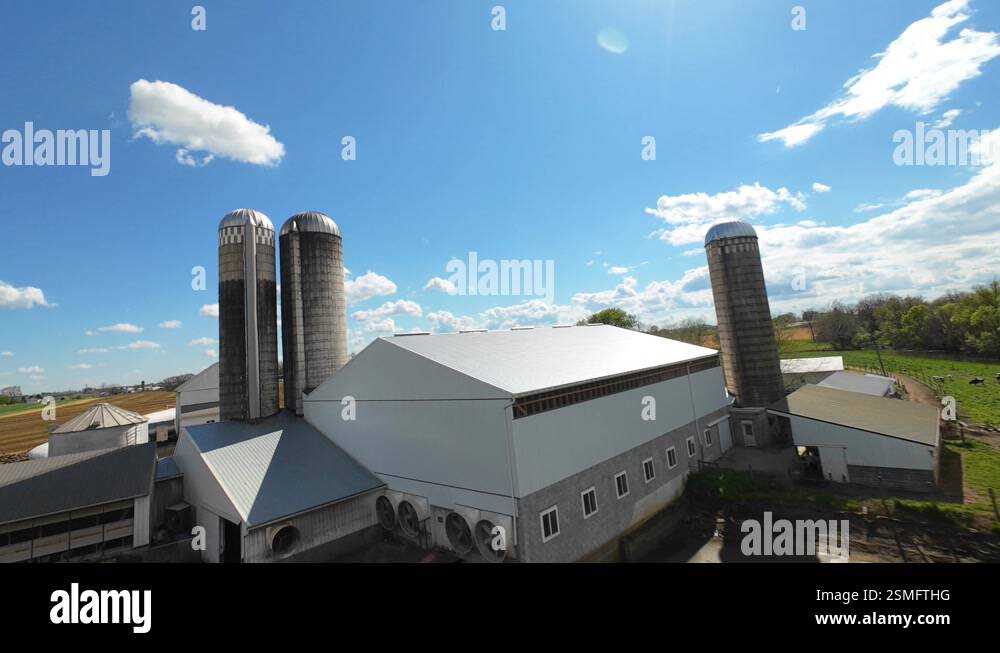 Drone flies over a large white barn with three visible silos, and other ...