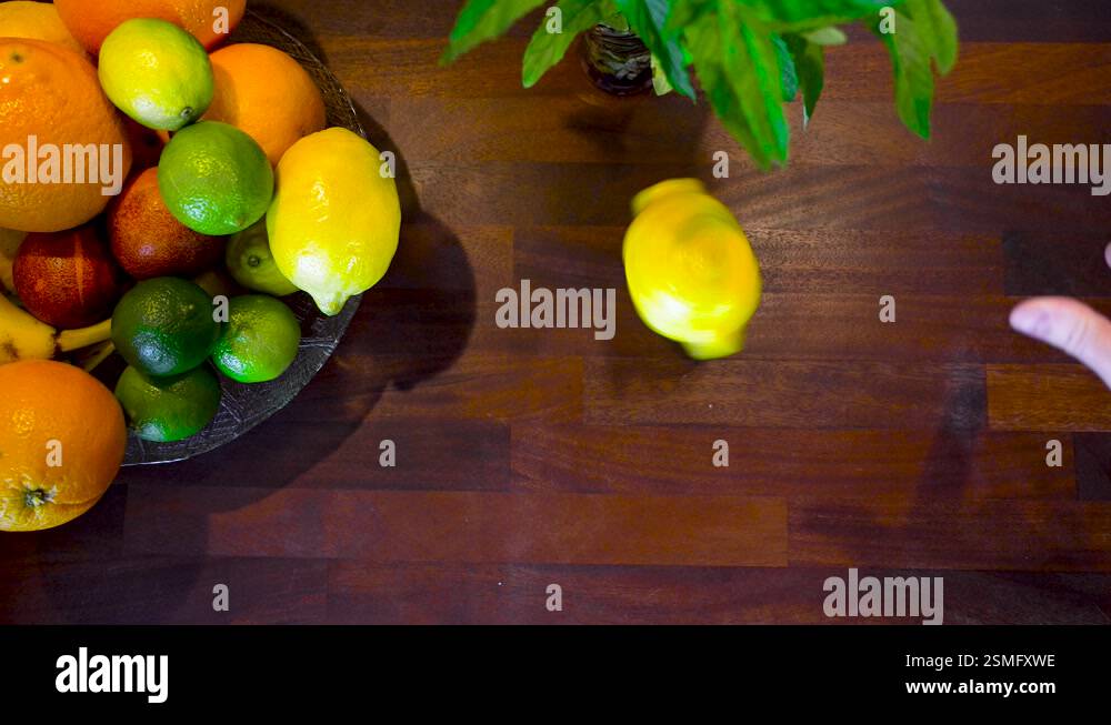 A hand spinning a Citrus yellow lemon clockwise on a table in slow ...