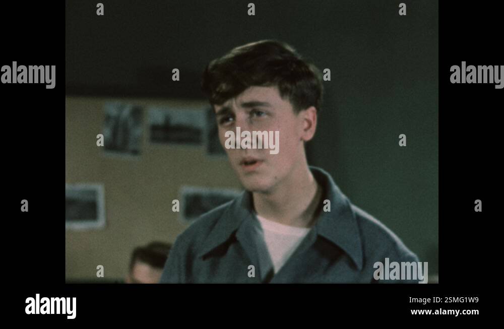 1950s: young man stands in classroom, talks earnestly, looks concerned ...