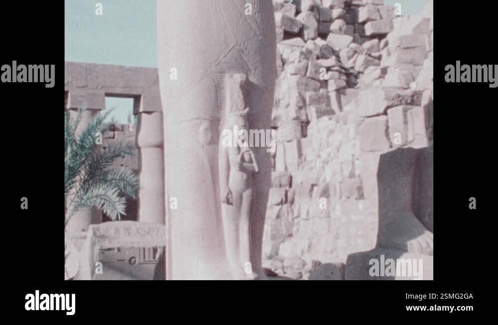 1970s: Ancient Egyptian statue stands near ruins. Crowds walk through ...