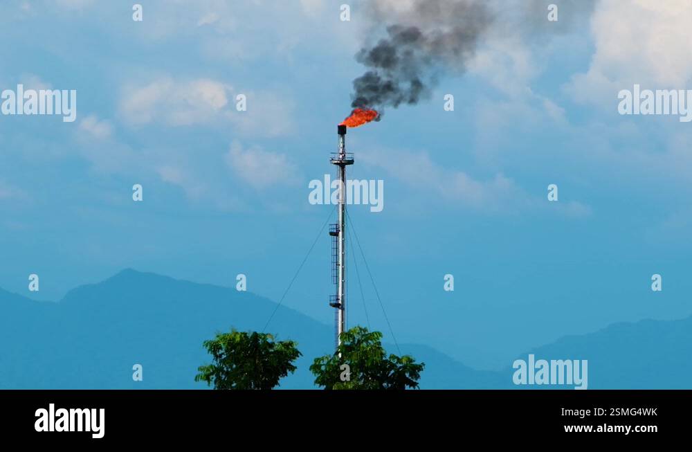 A flare stack burning off excess gas at an oil refinery with copy space ...