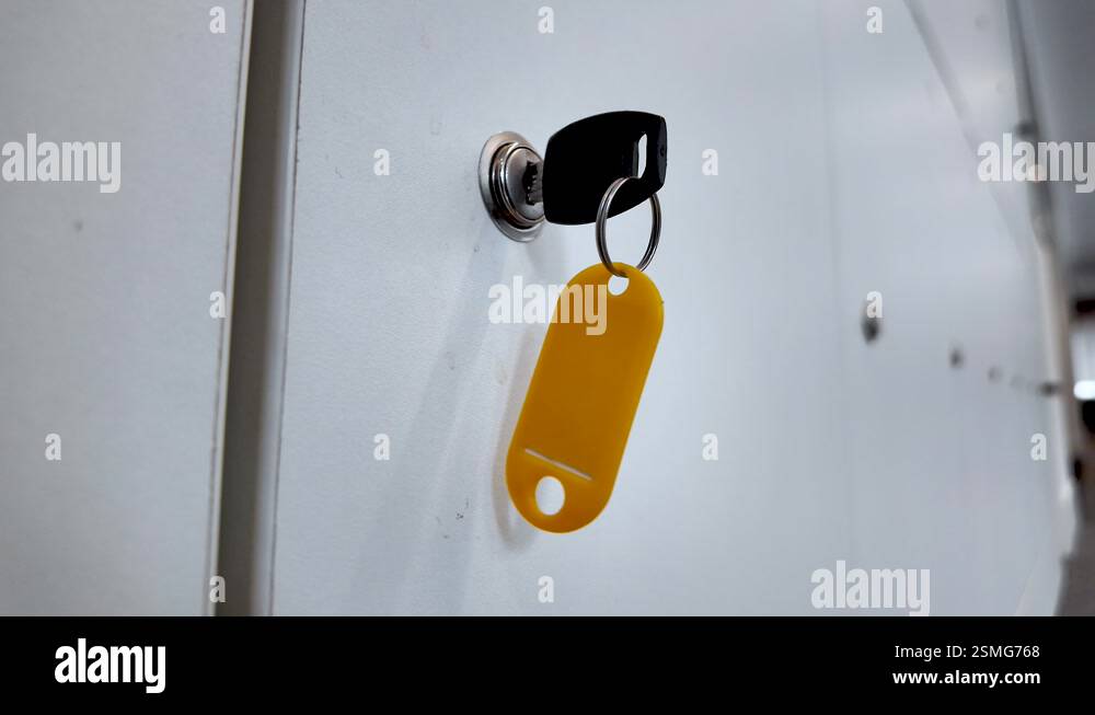 Close-up view of a key inserted in a keyhole with a yellow key tag ...
