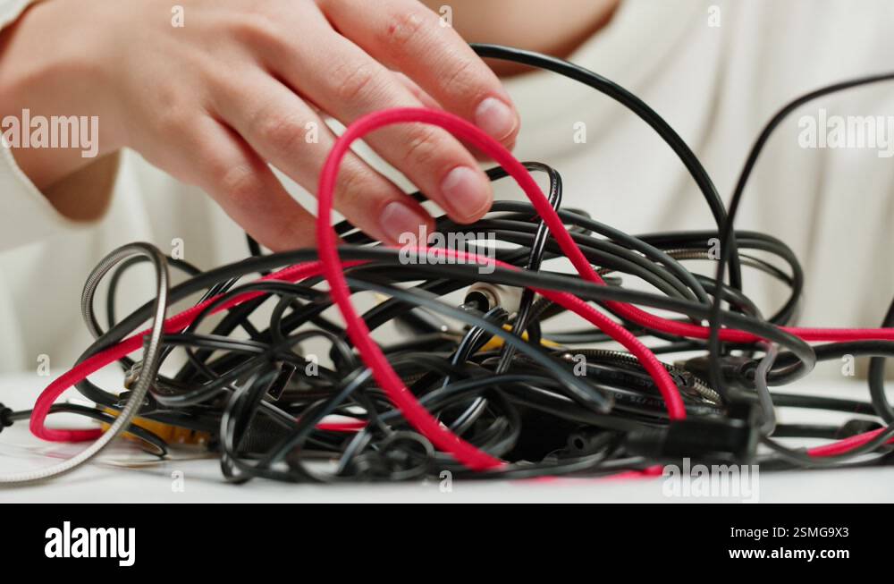Young woman trying to untangle many various of wires close-up. Tangled ...