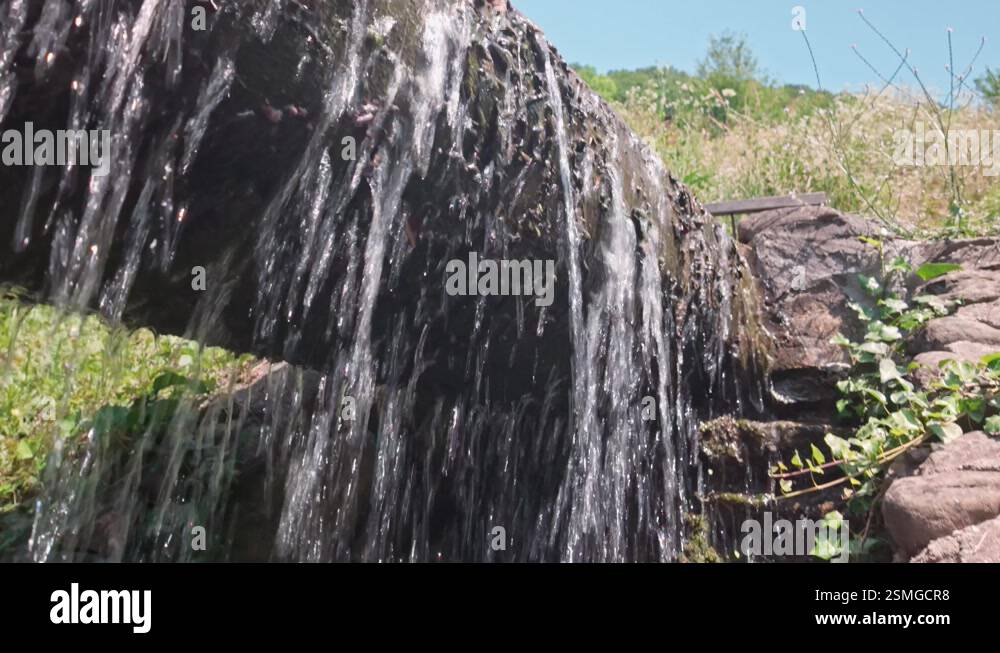 Overflowing water cascades from rustic wooden sluice log flume chute ...