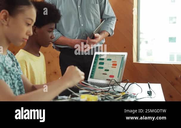 Teacher standing while explain coding and robotic construction. Diverse teenager fixing mother ...