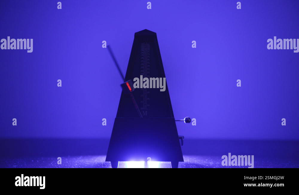 Metronome that is moving back and forth that is lit below by a blue ...
