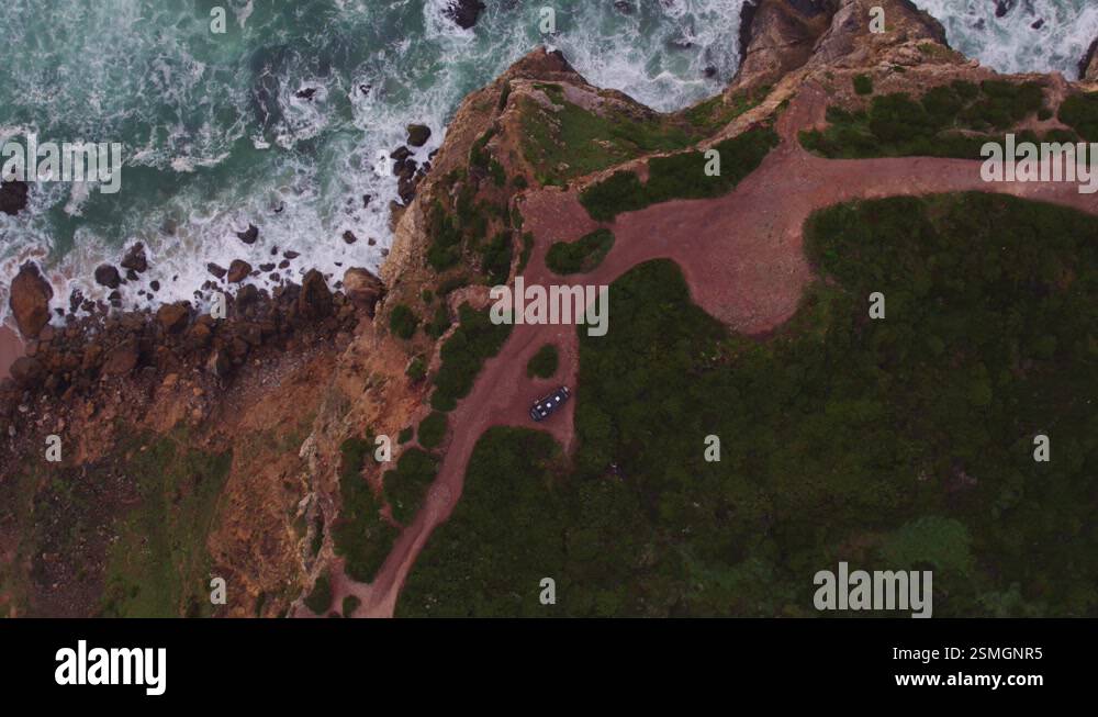 Aerial view of cliffside beach at Praia do Caneiro during sunset ...