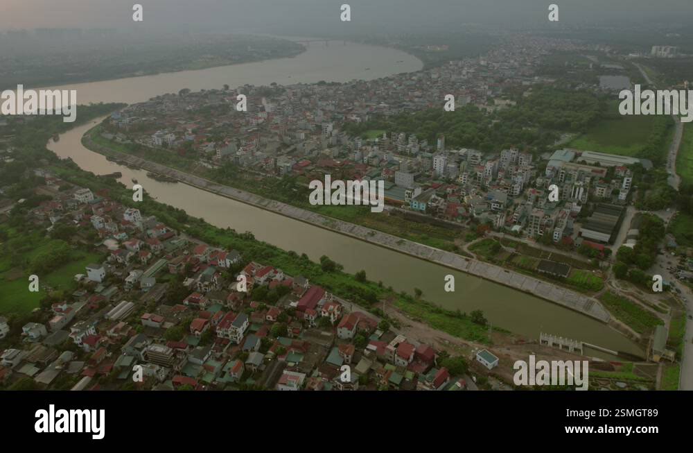 Aerial orbit Red River following through Hanoi residential area ...