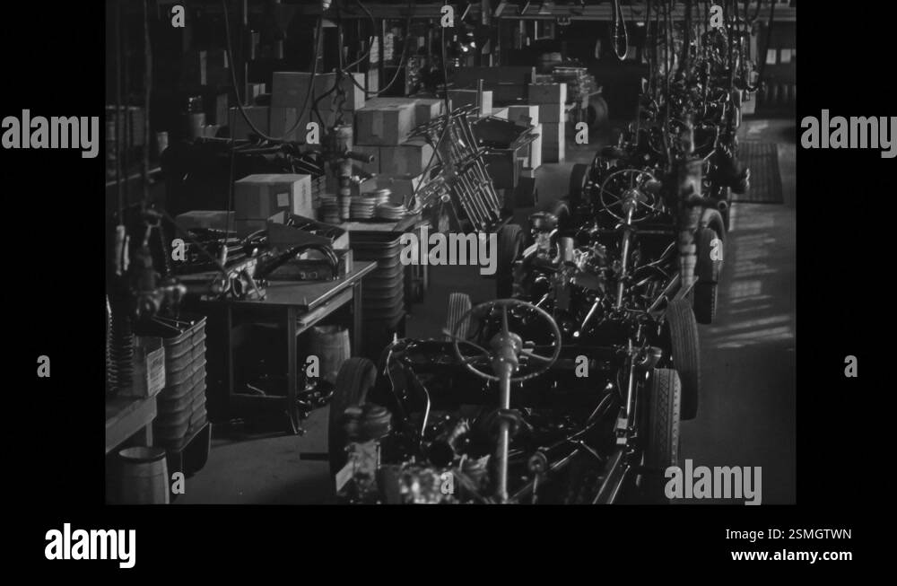 1940s: Black and white film footage of a car assembly line in a factory ...