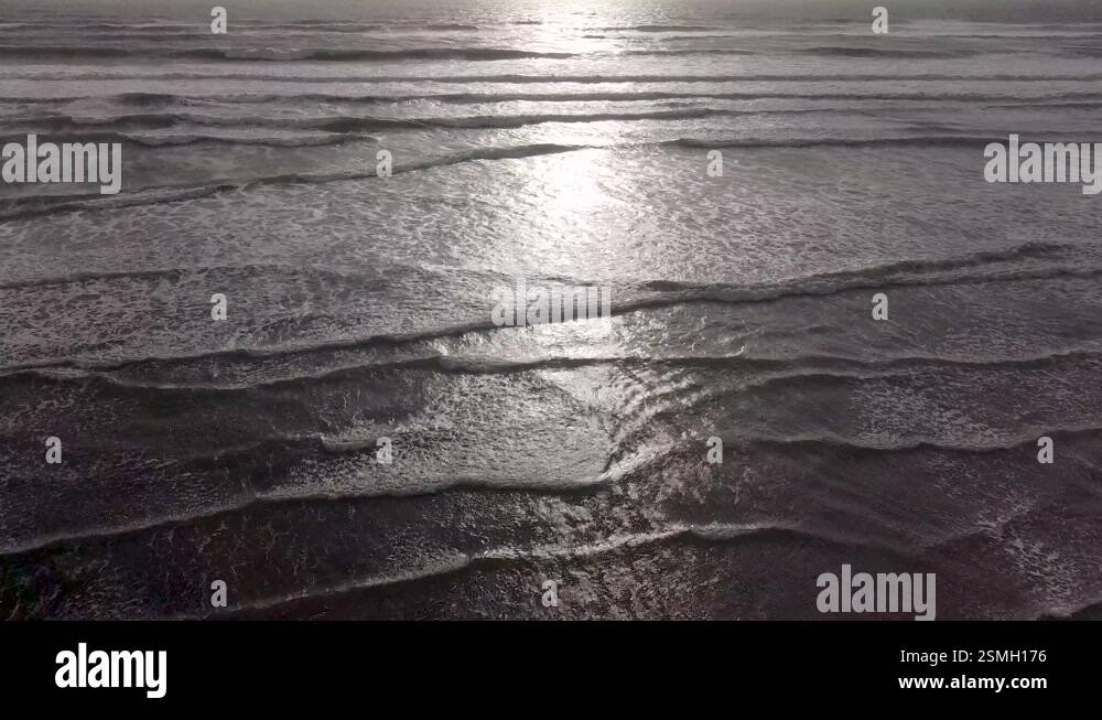 Symmetrical waves rise and break on the shores of Piha Beach in New ...