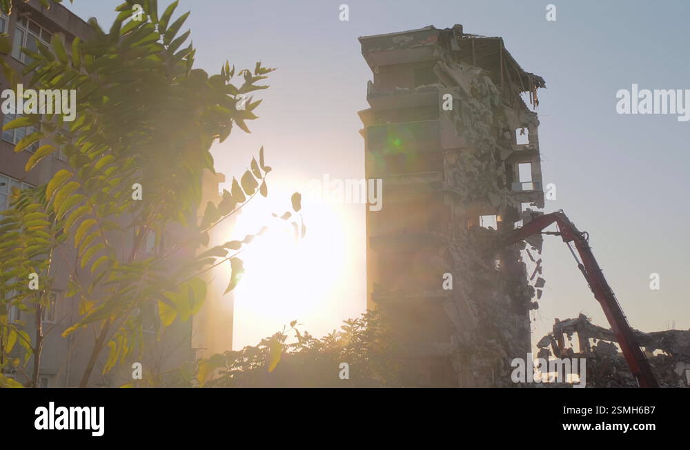 Excavator with hydraulic crusher is tearing down the residential ...