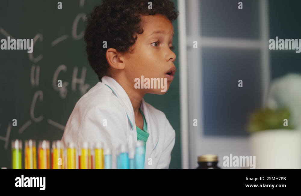 Little boy analyzing lab sample with a magnifying glass, shocked by ...