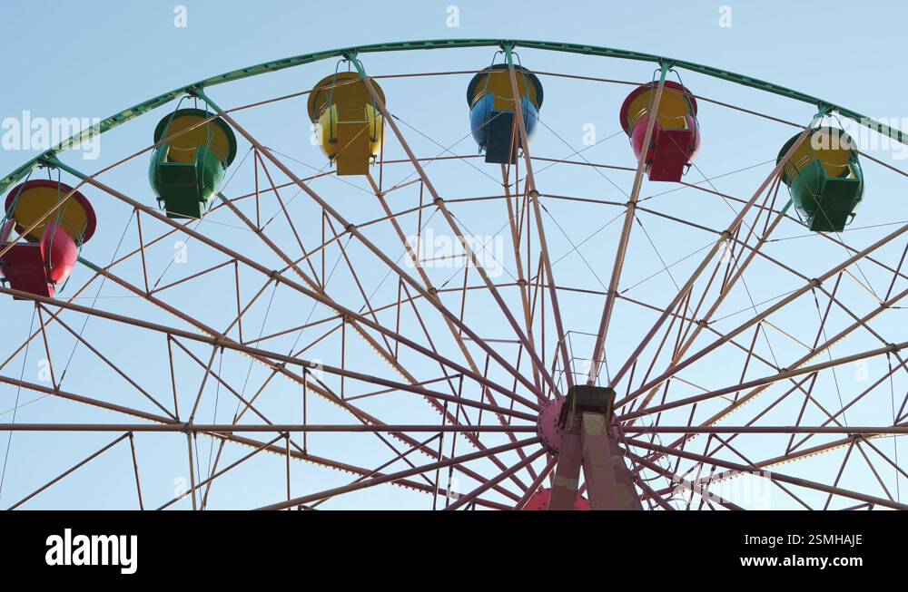 Bottom view of multicolored Observation wheel cabins against blue sky ...