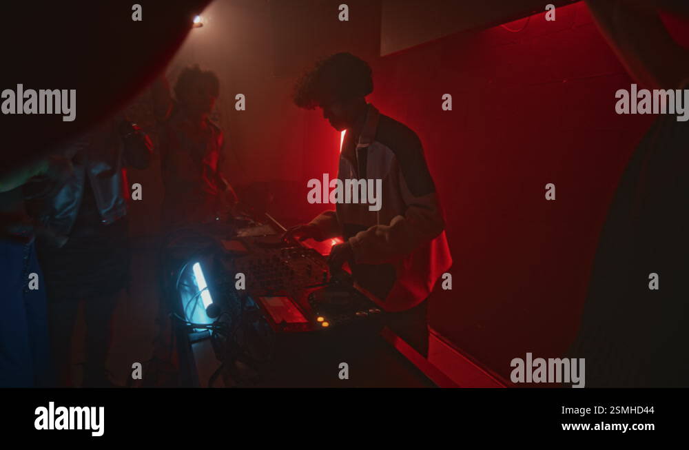 DJ Playing Electronic Music to Dancing Crowd in Red Neon Lit Nightclub ...