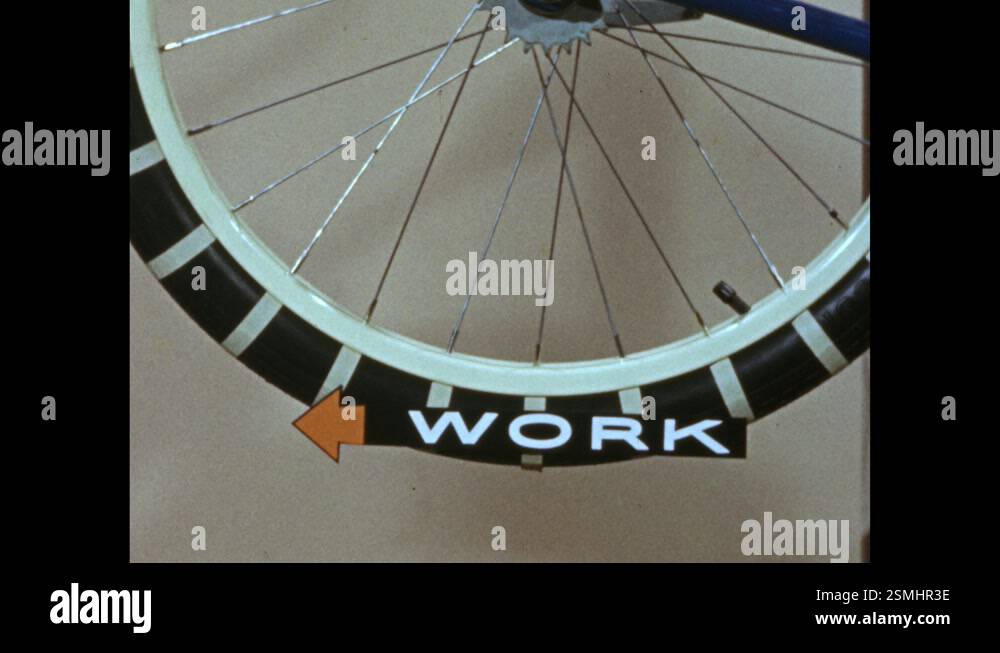1960s: Back wheel of bicycle with arrow pointing behind. Person holds ...