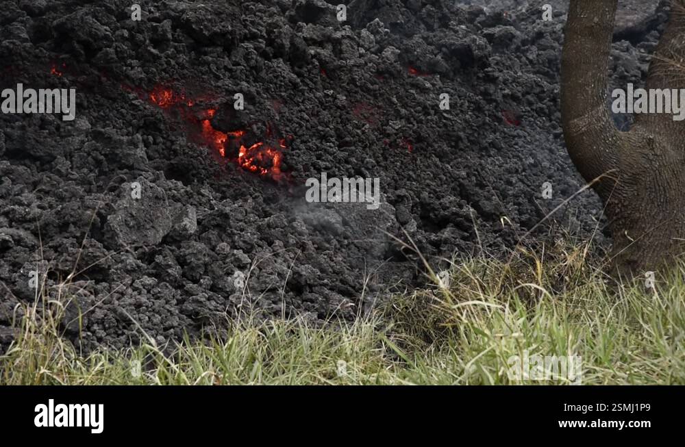 Close-up footage of lava rocks falling on burning grass from the ...