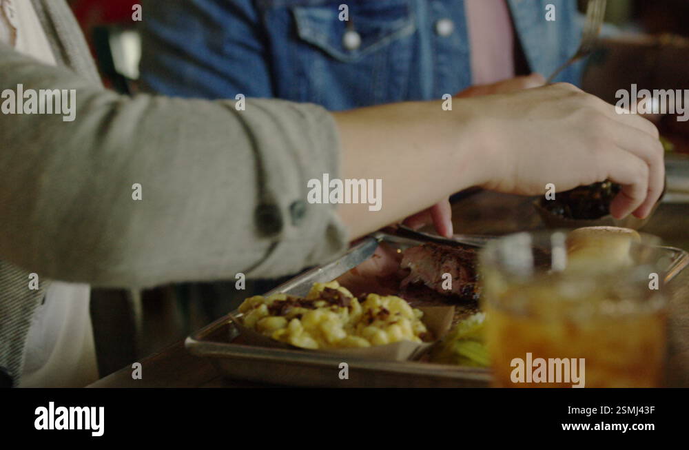 Two people eat barbecue food with a side of macaroni and cheese at a ...