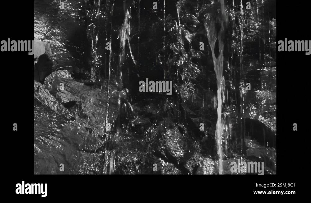 1940s: Water drips from rocks in a forest, creating a cascading ...